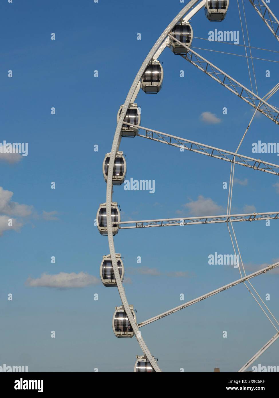 Partial view of a Ferris wheel with several cabins in front of a clear ...