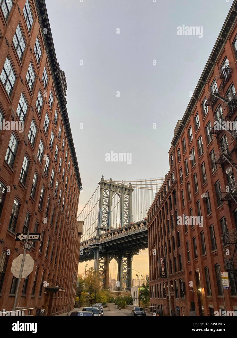 View of a bridge framed by tall red brick buildings at dusk, new york ...