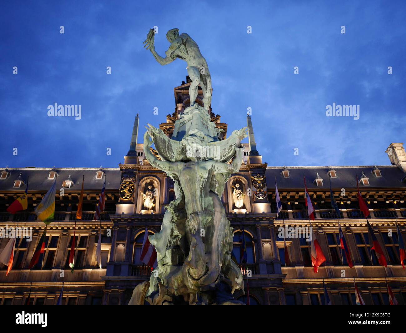 Illuminated bronze statue on a fountain in front of a historic baroque ...
