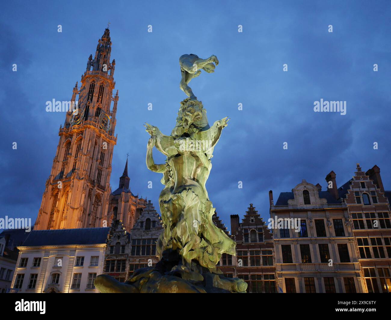 Nocturnal view of the square with illuminated statue and church tower ...