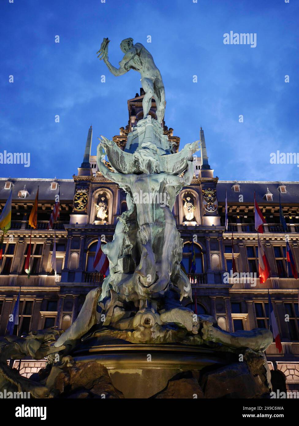 Statue on a fountain in front of an illuminated historical building at ...