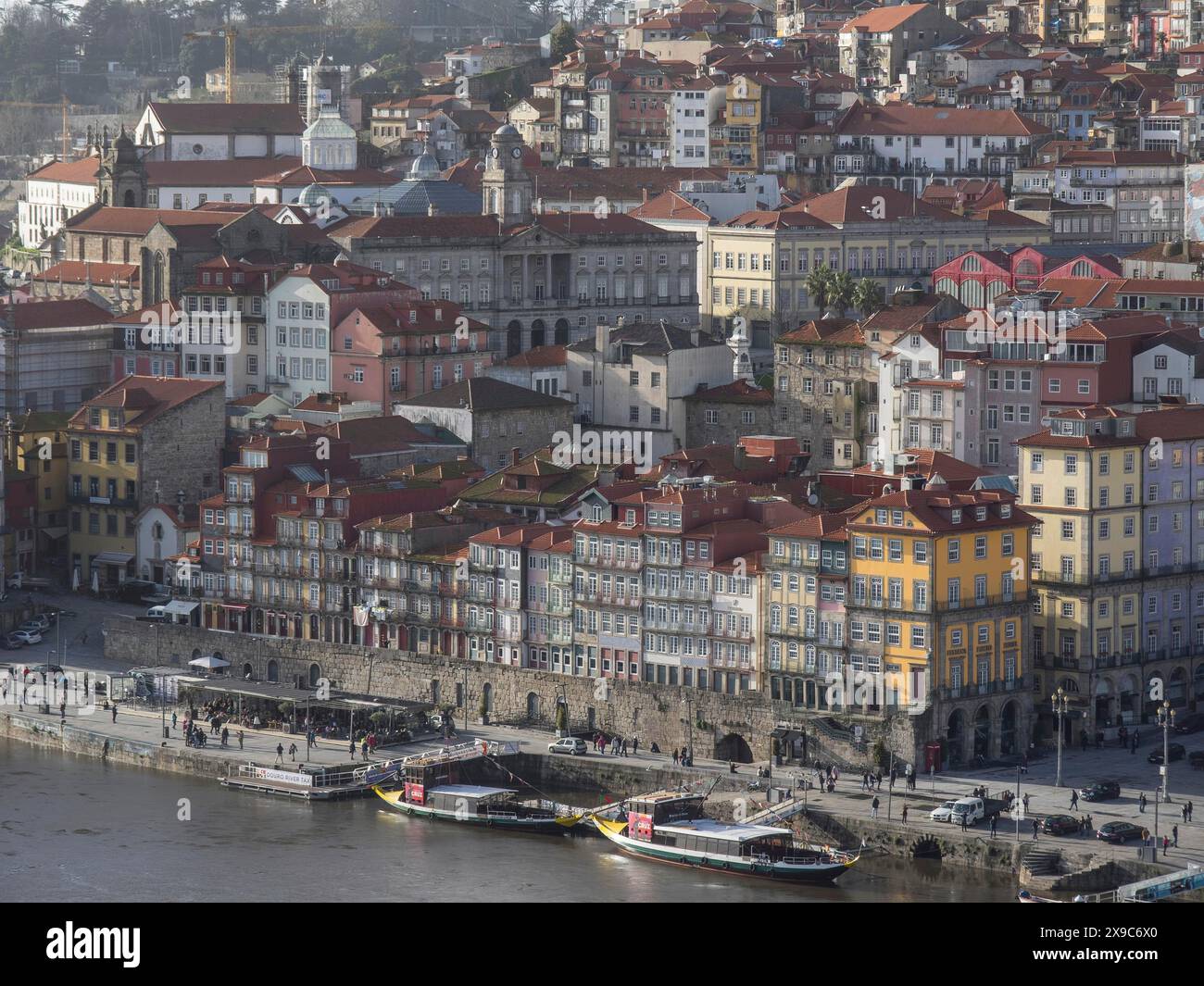 Urban landscape by a river, lined with houses with red roofs and ...
