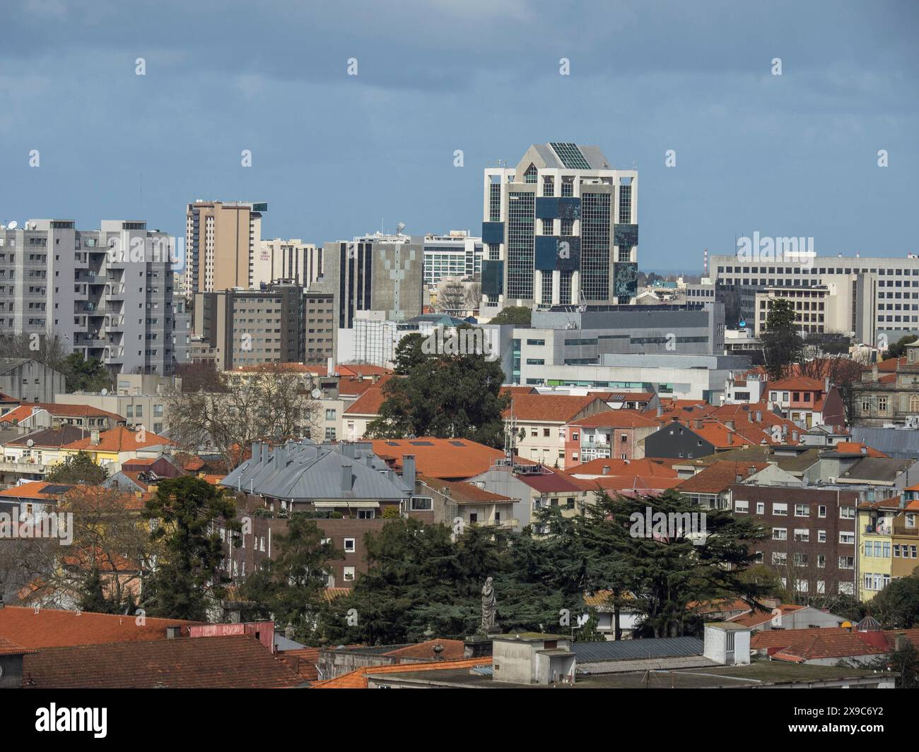 Urban landscape with modern high-rise buildings, low roofs and trees in ...