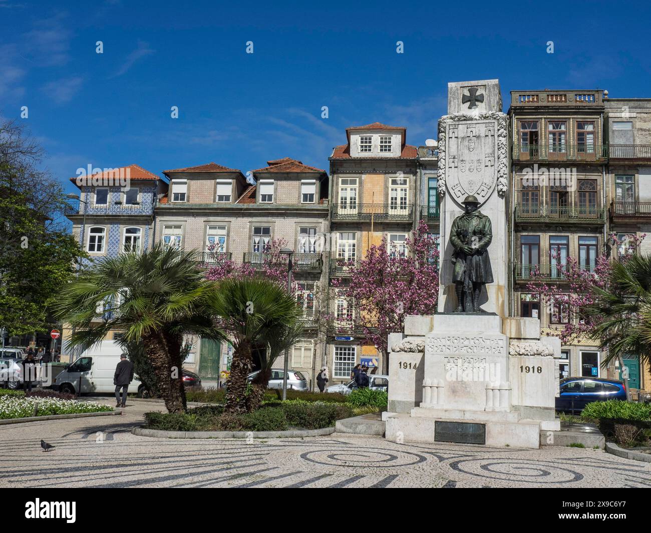 Monument in front of townhouses and blossoming trees with palm trees in ...