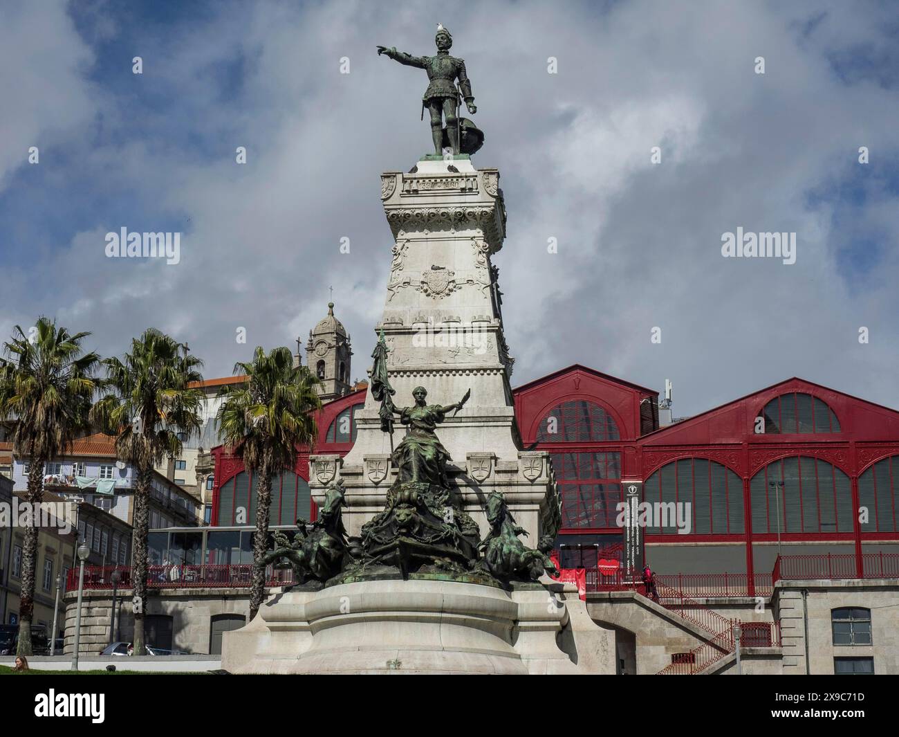 Monument with statue in front of a building with a red roof under a ...