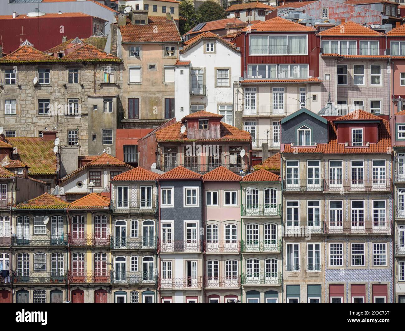 Facades of narrow, colourful houses in the old town with red roof tiles ...