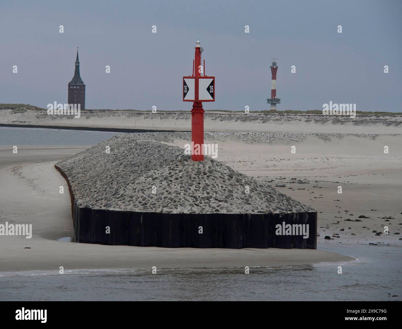 Red beacon on gravel embankment, church tower and lighthouse in the ...