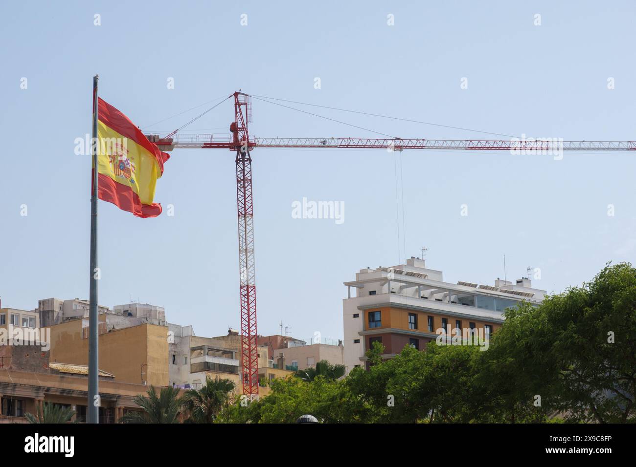 Economy and housing in Spain. Construction crane behind the flag of ...