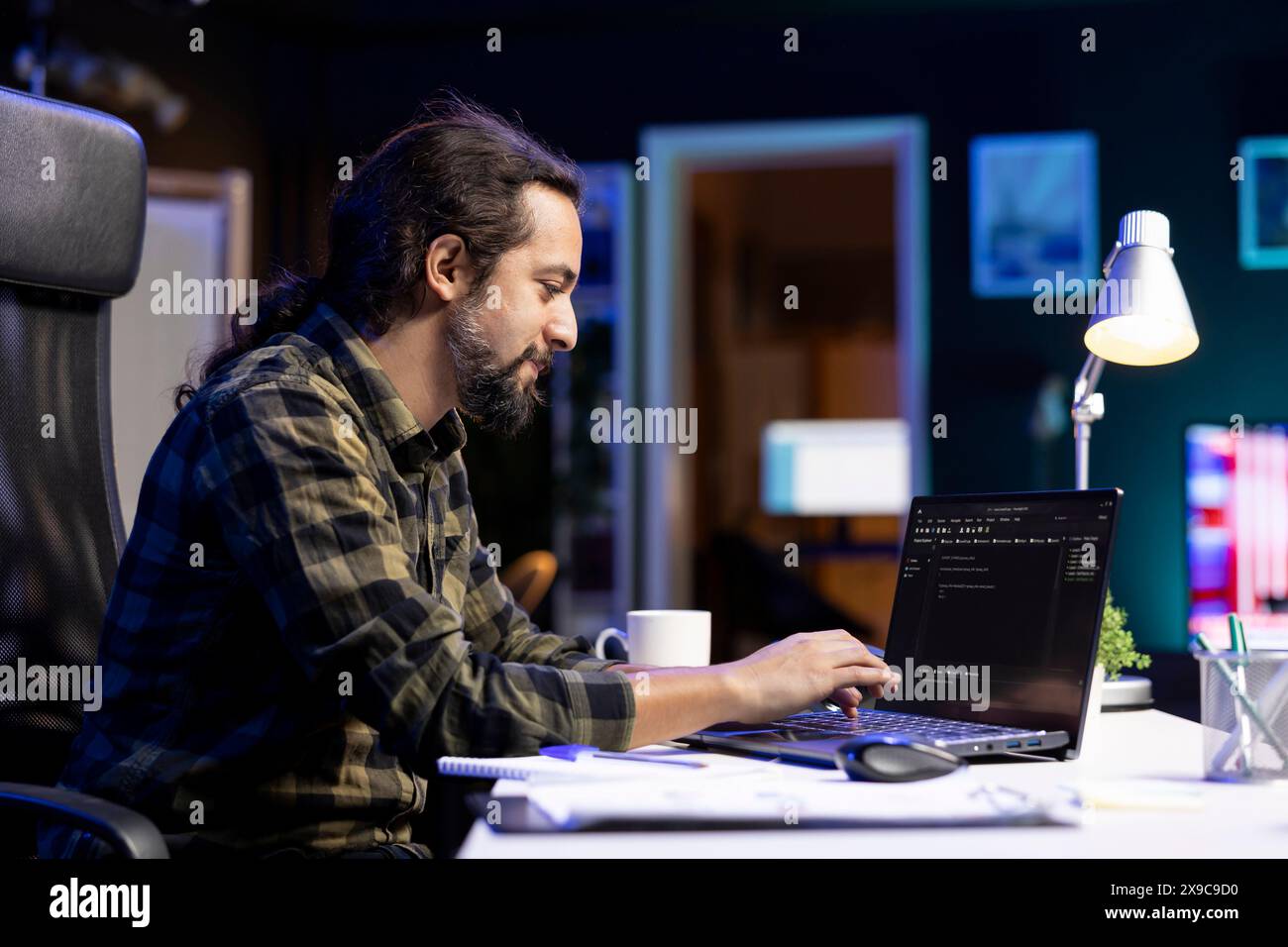 Male programmer works on his portable computer, managing the database ...