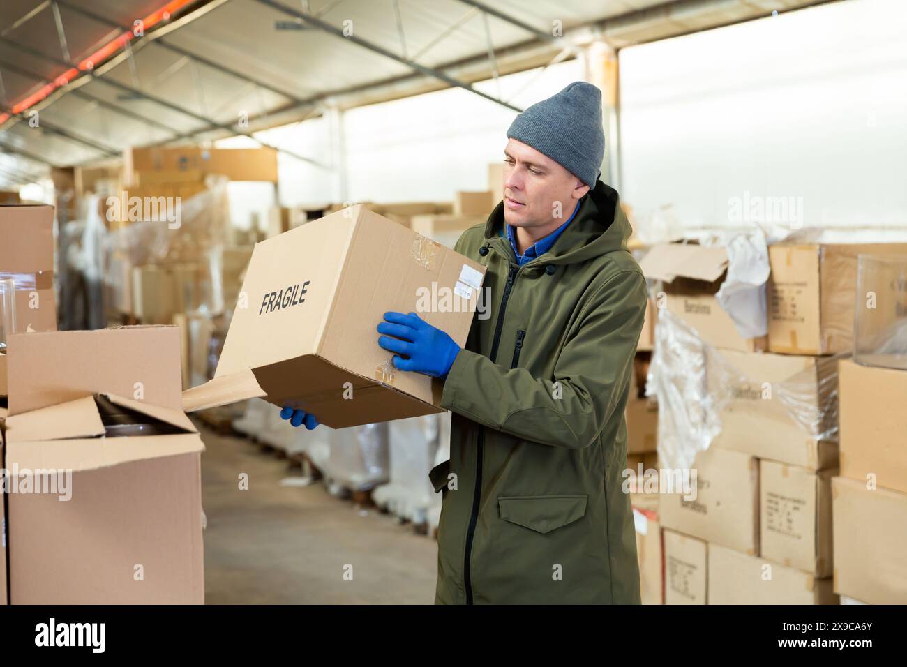 Loader stacks various boxes on racks in store Stock Photo - Alamy