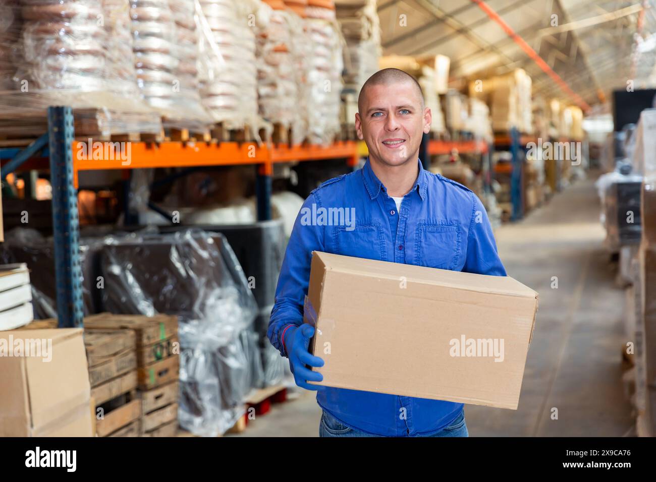 Positive warehouse worker dragging boxes on hands Stock Photo - Alamy