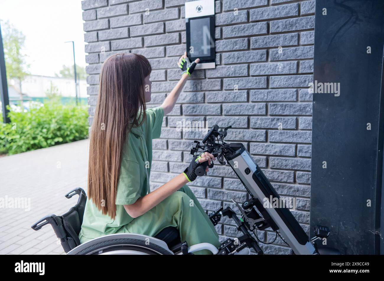 A woman in a wheelchair with an assistive device for manual control ...