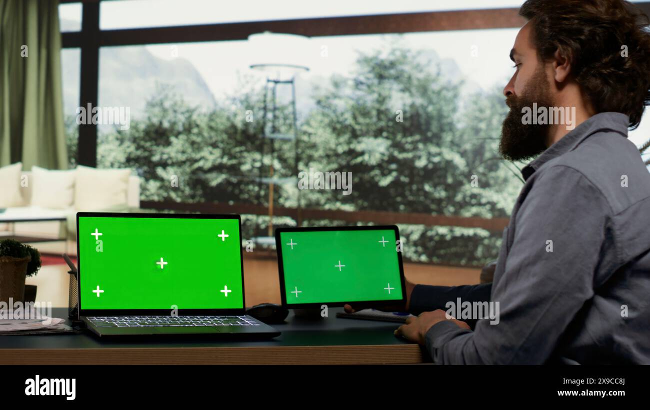Wealthy person using greenscreen on two devices, sitting at his ...