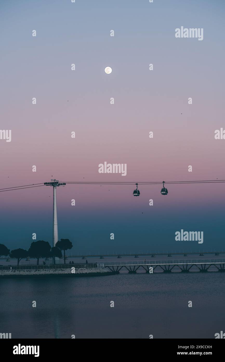 A serene twilight scene with a full moon rising over a cable car system ...