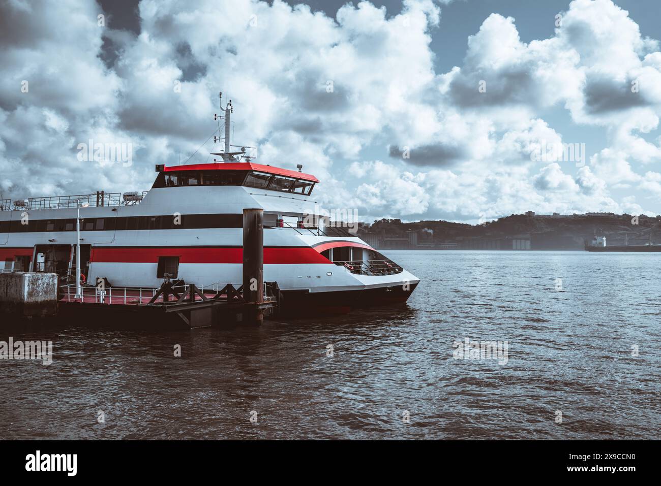 A modern passenger ferry docked at a pier on a cloudy day. The ferry ...
