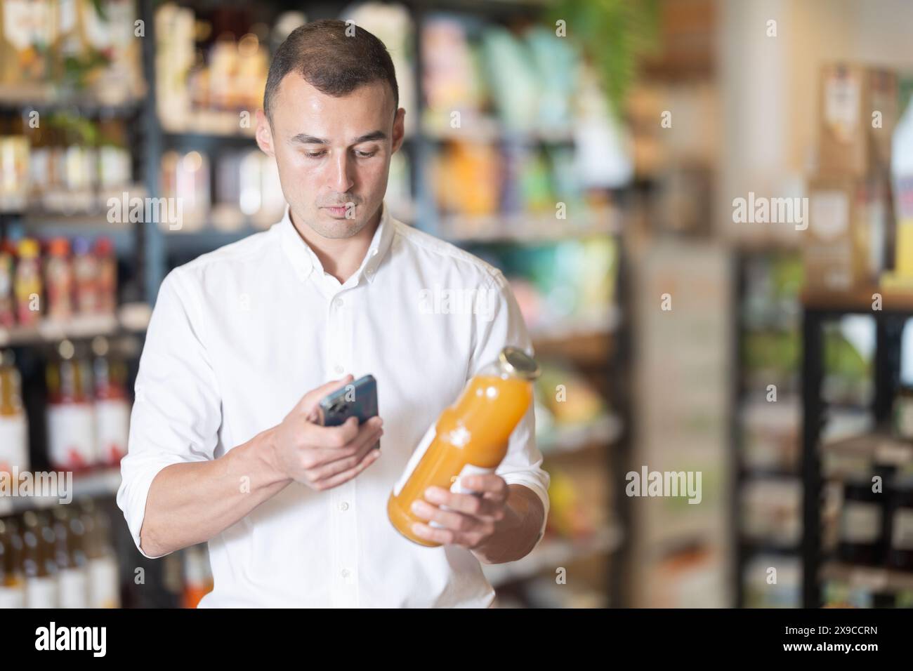 Man in supermarket scan QR code on bottle of drink Stock Photo - Alamy