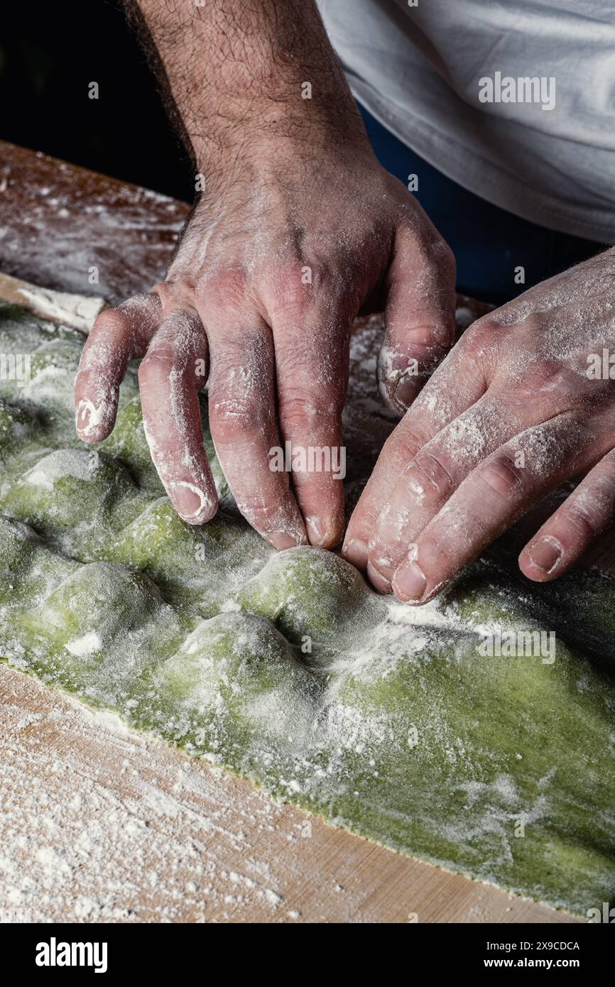 Male hands skilfully shape handmade ravioli filled with ricotta and ...