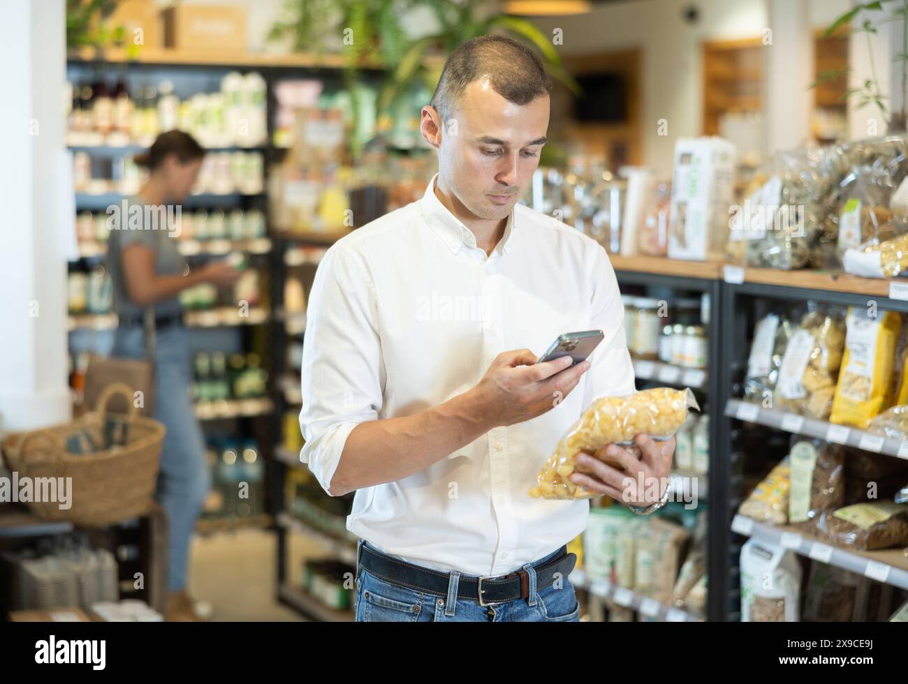 Young man purchaser scanning QR code of pasta in grocery store Stock ...