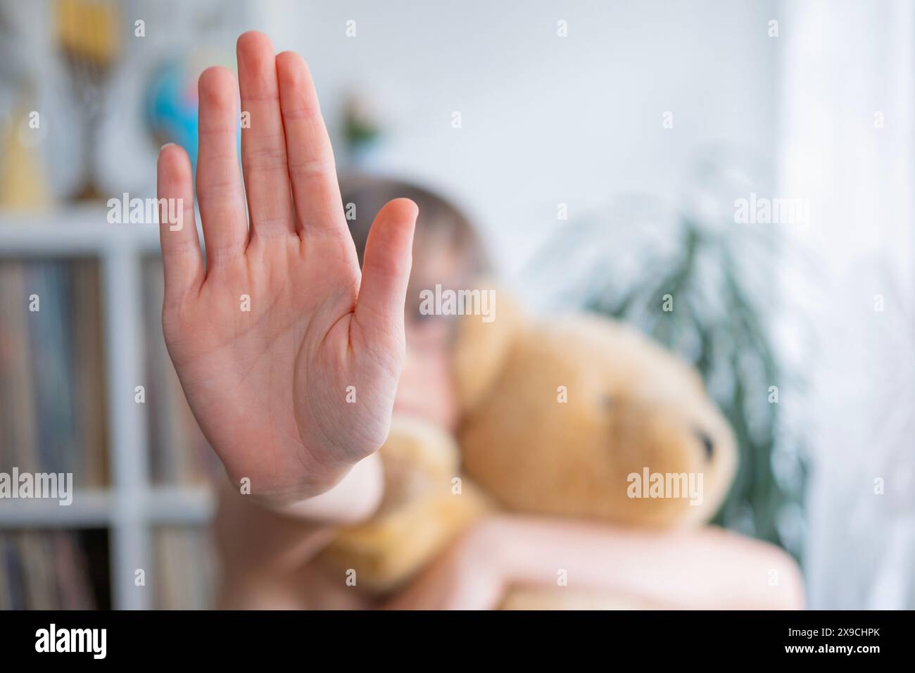 child with toy teddy bear, 11-year-old boy with defensive hand gesture ...