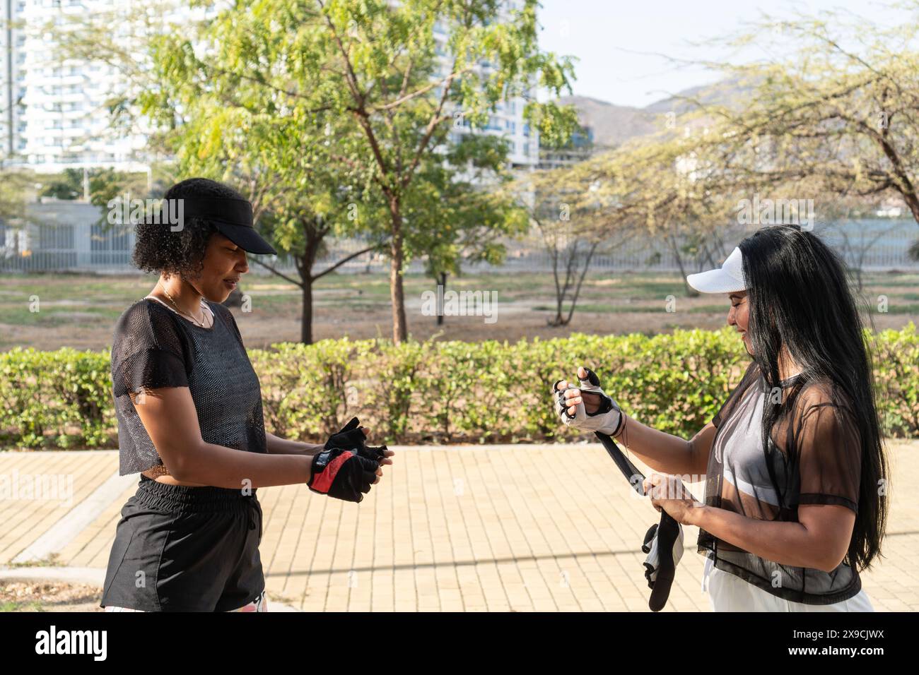 Two women getting ready for a workout in a park, wearing athletic gear ...
