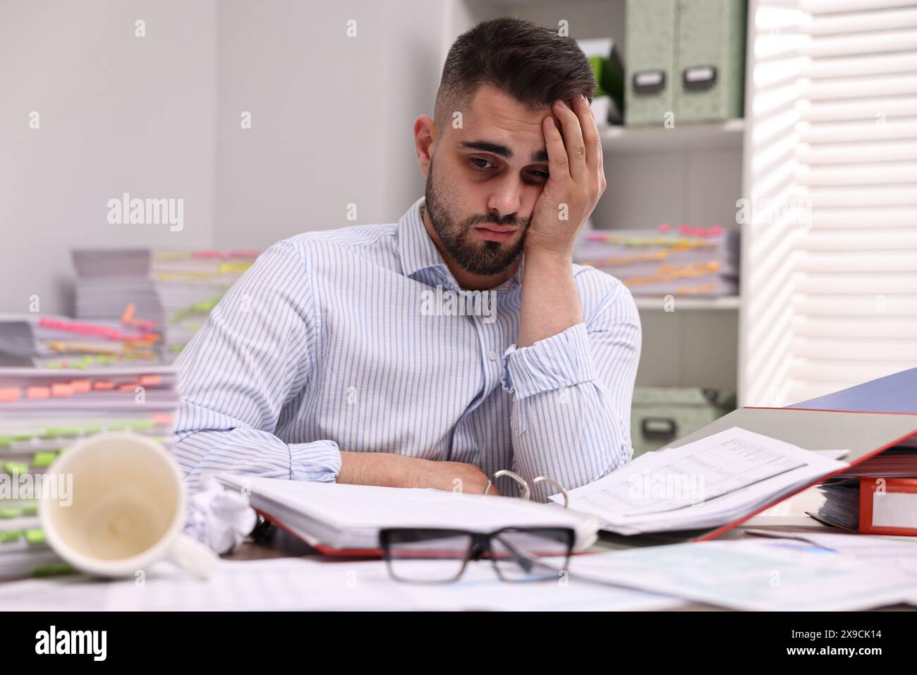 Overwhelmed man surrounded by documents at workplace in office Stock ...