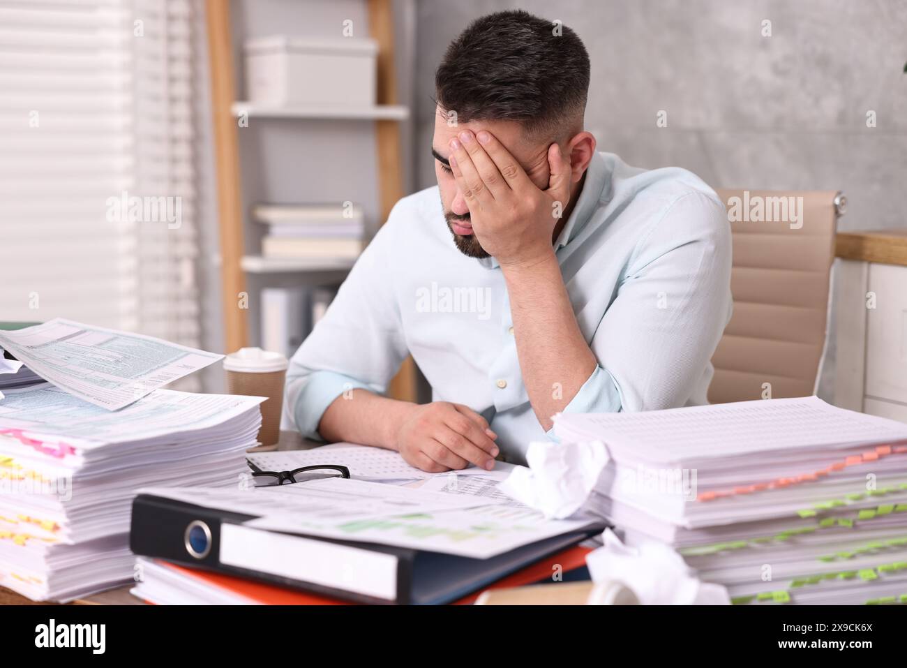 Overwhelmed man surrounded by documents at workplace in office Stock ...