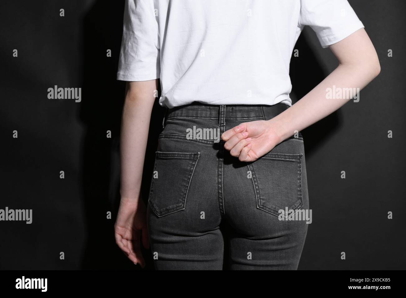 SOS gesture. Woman showing signal for help behind her back on black ...