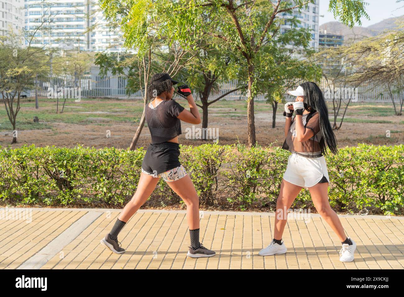 Two women practicing sparring techniques in an outdoor fitness combat ...