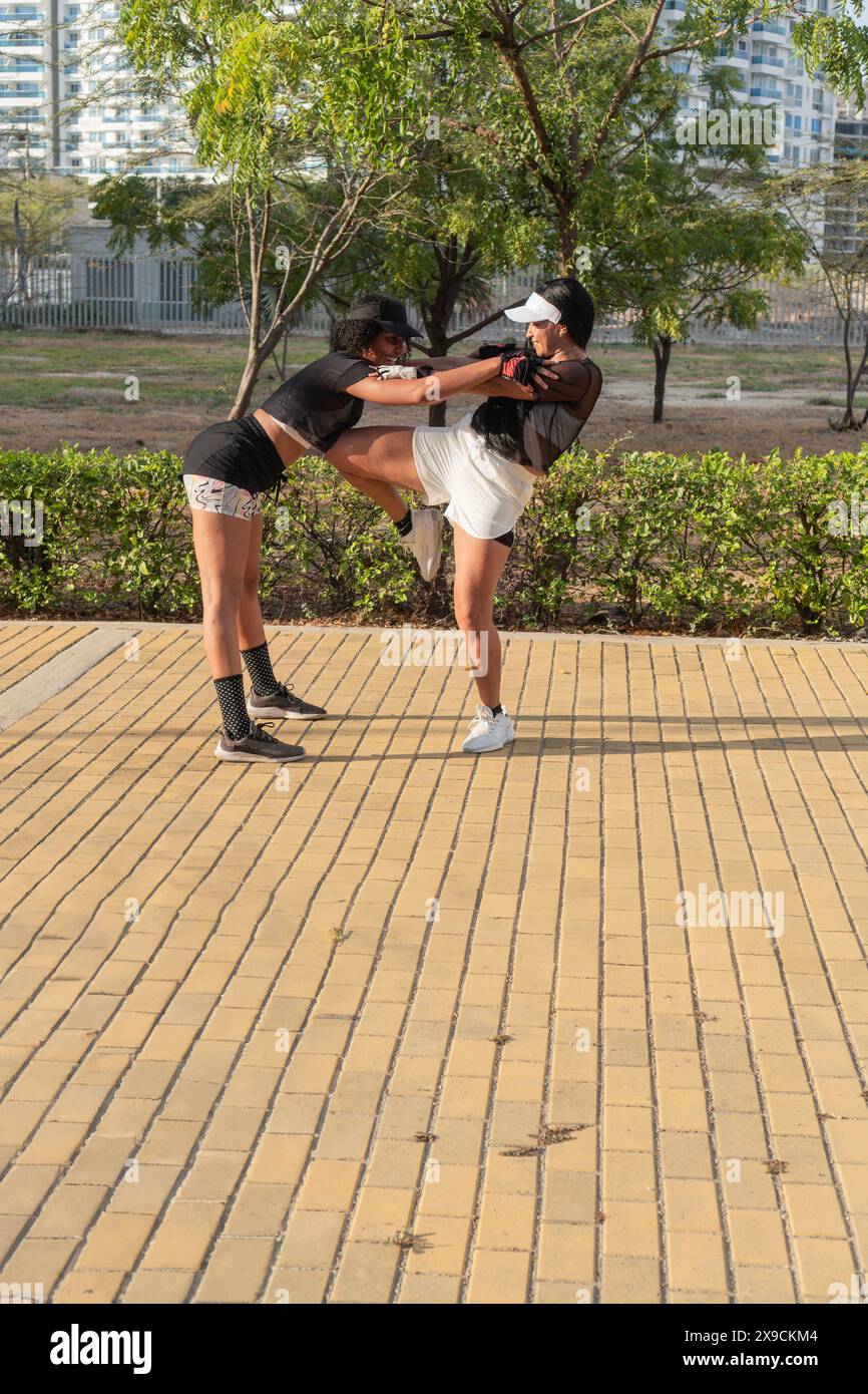 Two women performing a combat training kick maneuver in an outdoor ...