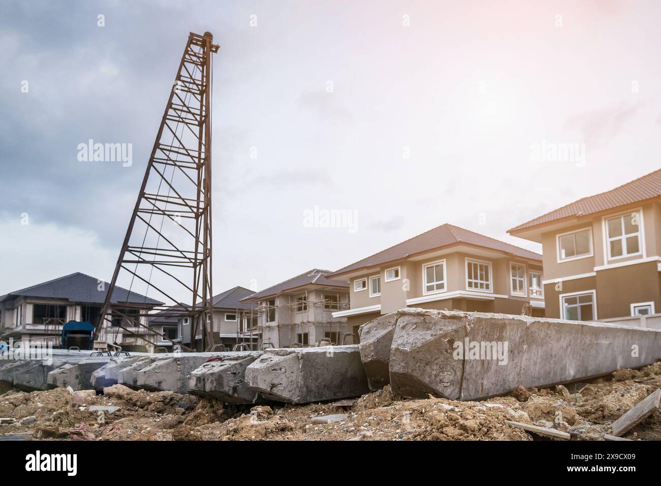 house building at construction site with pile driver and precast ...