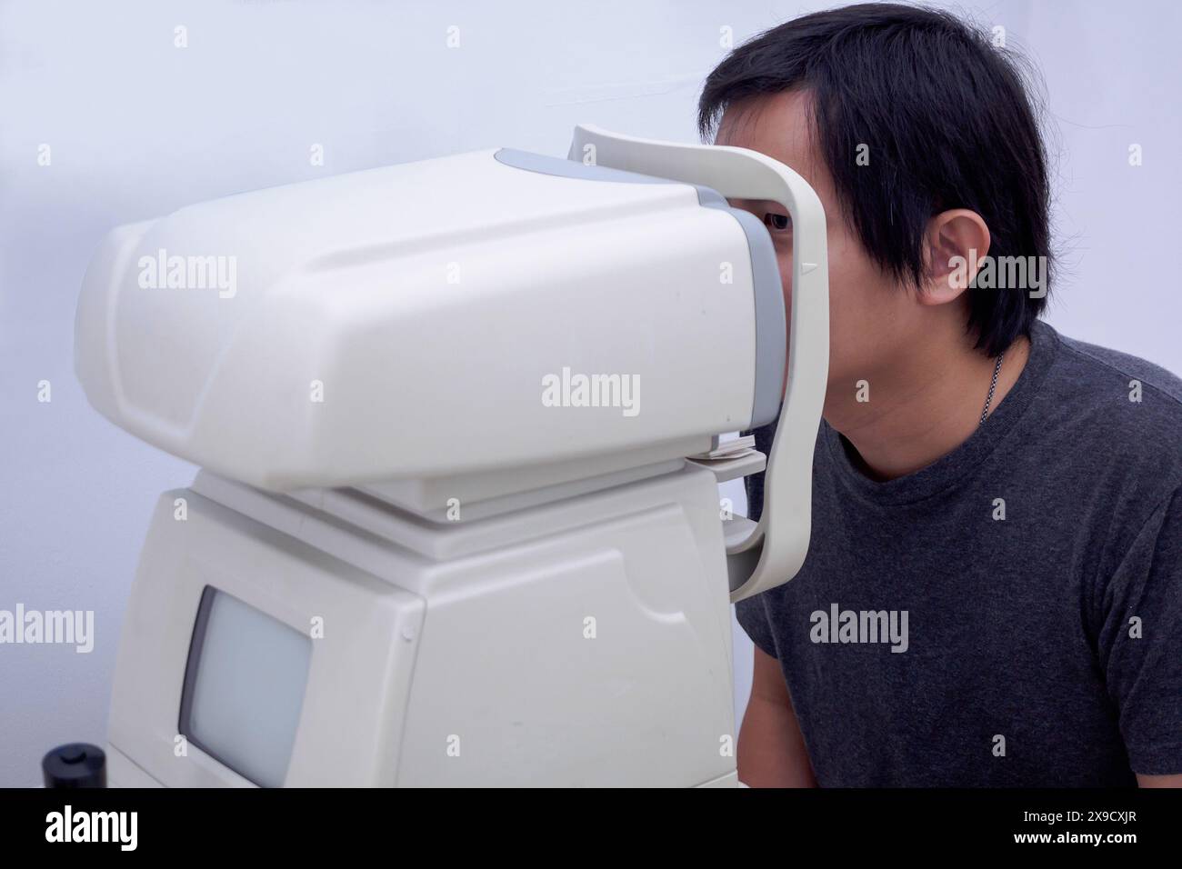 Young handsome asian man take eye exam with optical eye test machine ...