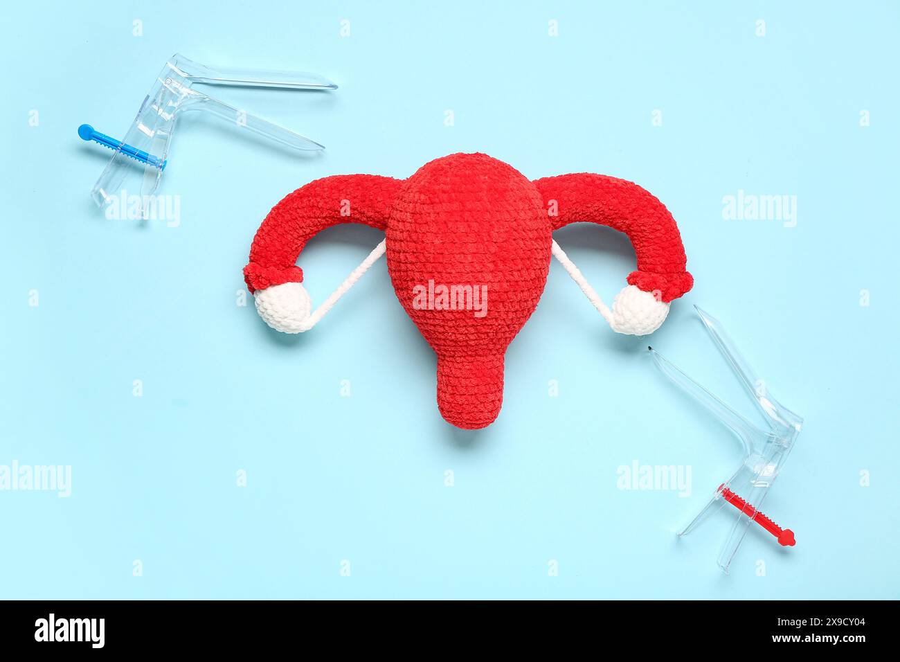 Knitted uterus with gynecological speculums on blue background Stock ...