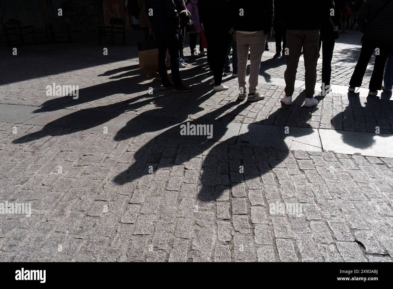Group of people standing, casting shadows on the pavement in the city ...