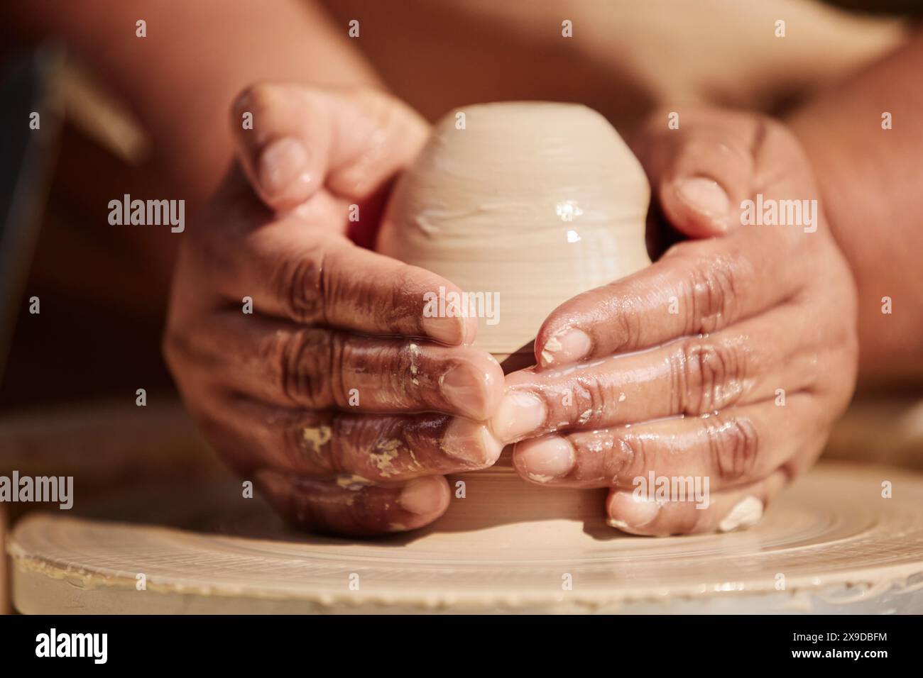 Front view closeup of gentle female hands shaping clay on pottery wheel ...