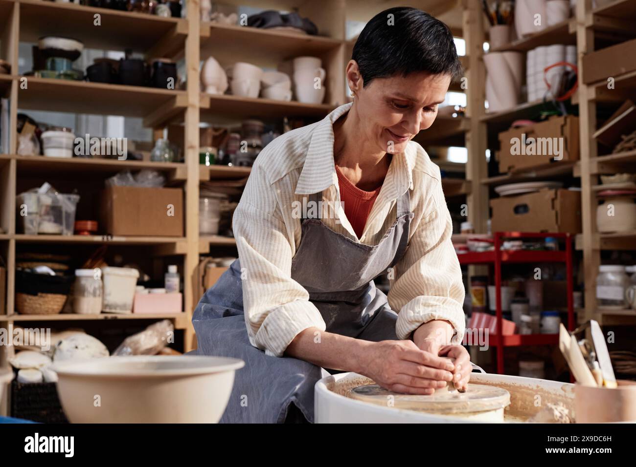 Portrait of smiling mature woman creating handmade ceramics on pottery ...