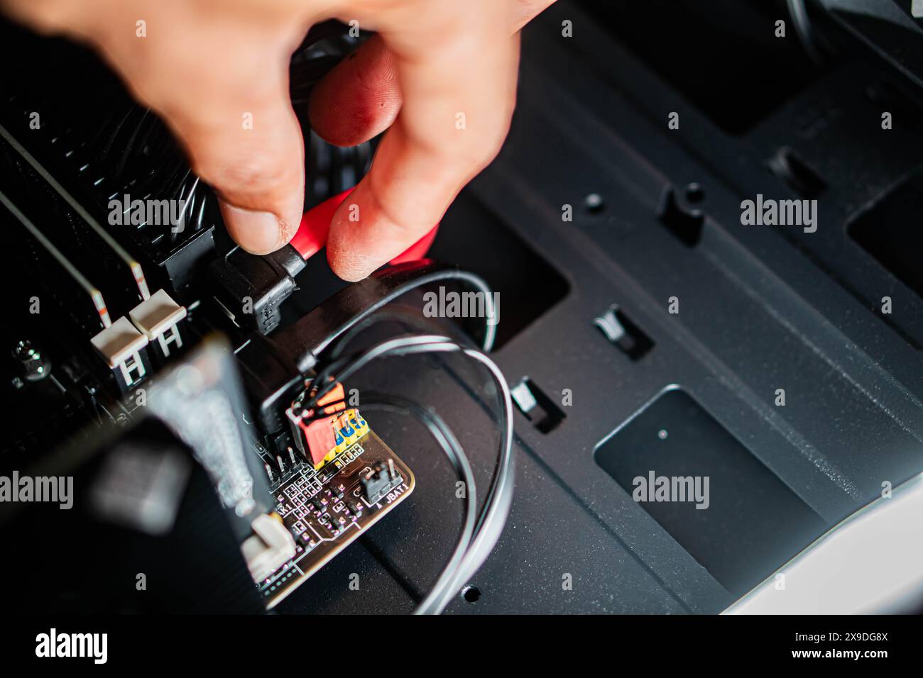 Close-up of a hand connecting a cable to a computer motherboard inside ...