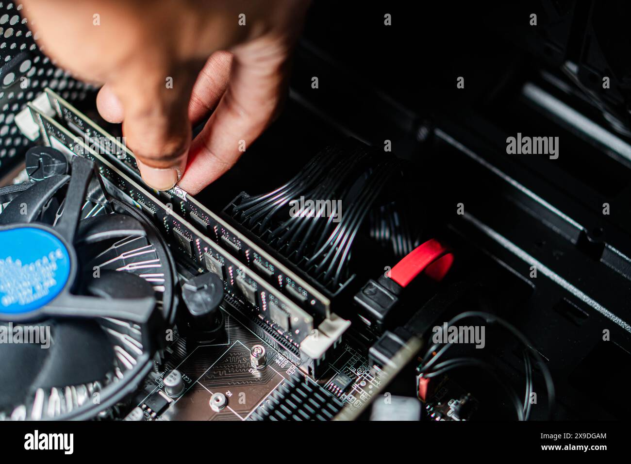 Close-up of a person installing RAM into a computer motherboard. The ...
