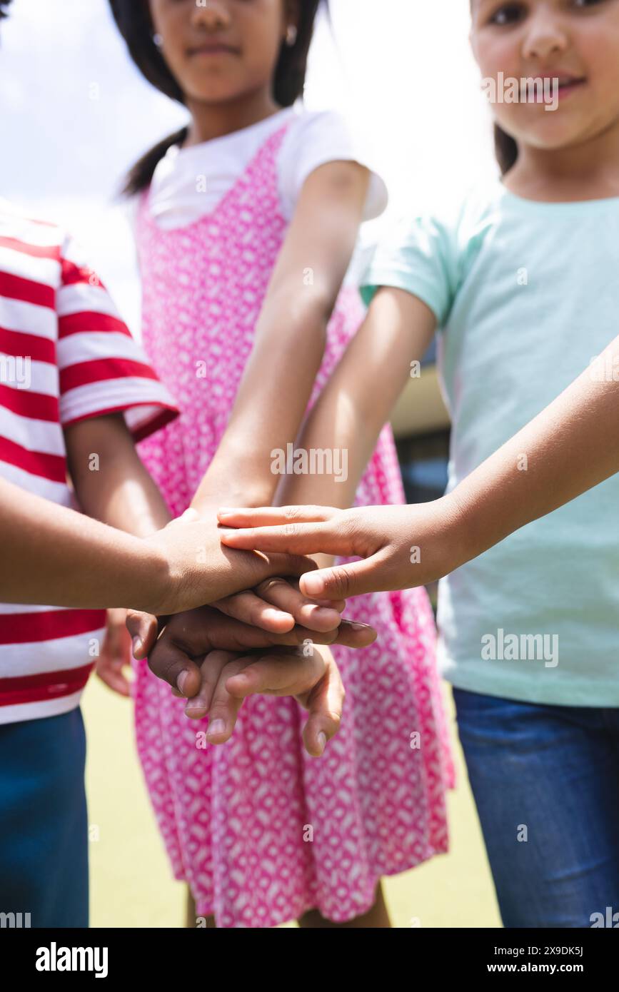 In school, diverse children are stacking hands together outside Stock ...