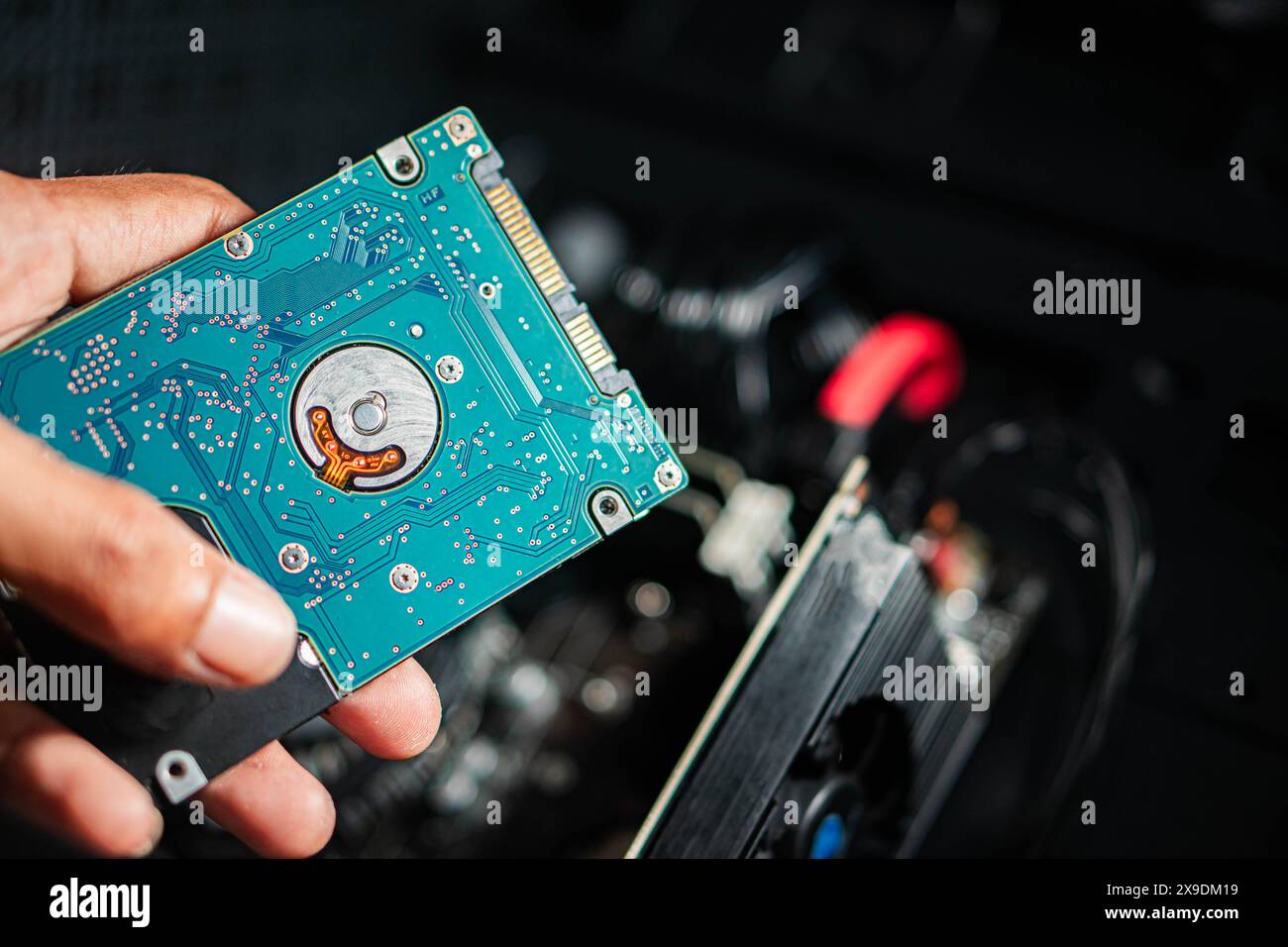 A person holding a blue circuit board of a hard disk drive with a ...