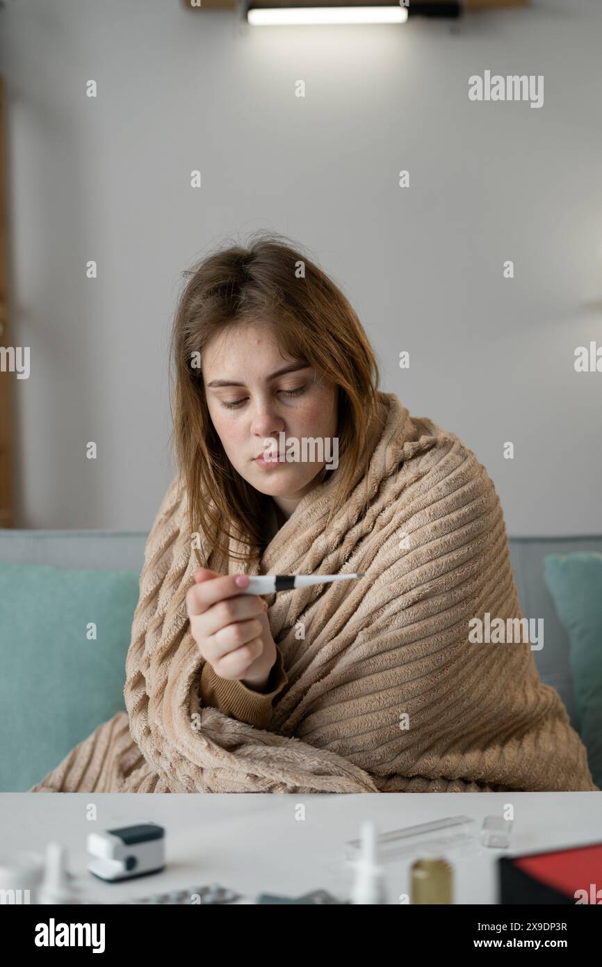 Sick young Caucasian woman with high fever measures temperature with ...
