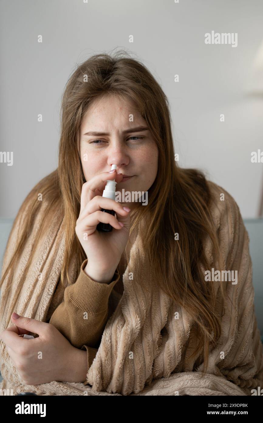 Fighting a cold, Caucasian girl under a blanket in a home atmosphere ...