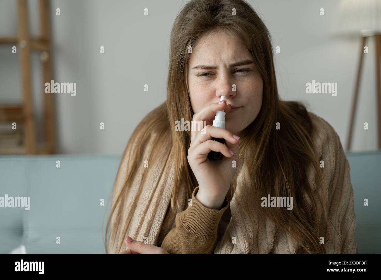 Fighting a cold, a Caucasian girl under a blanket in a home atmosphere ...