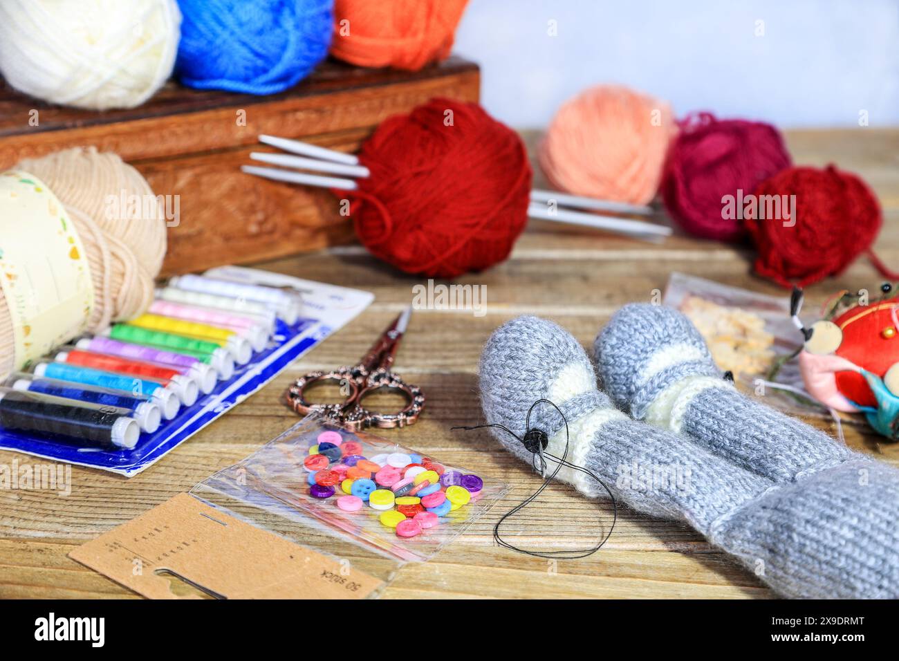 Working table with unfinished knitted teddy bear with knitting tools ...