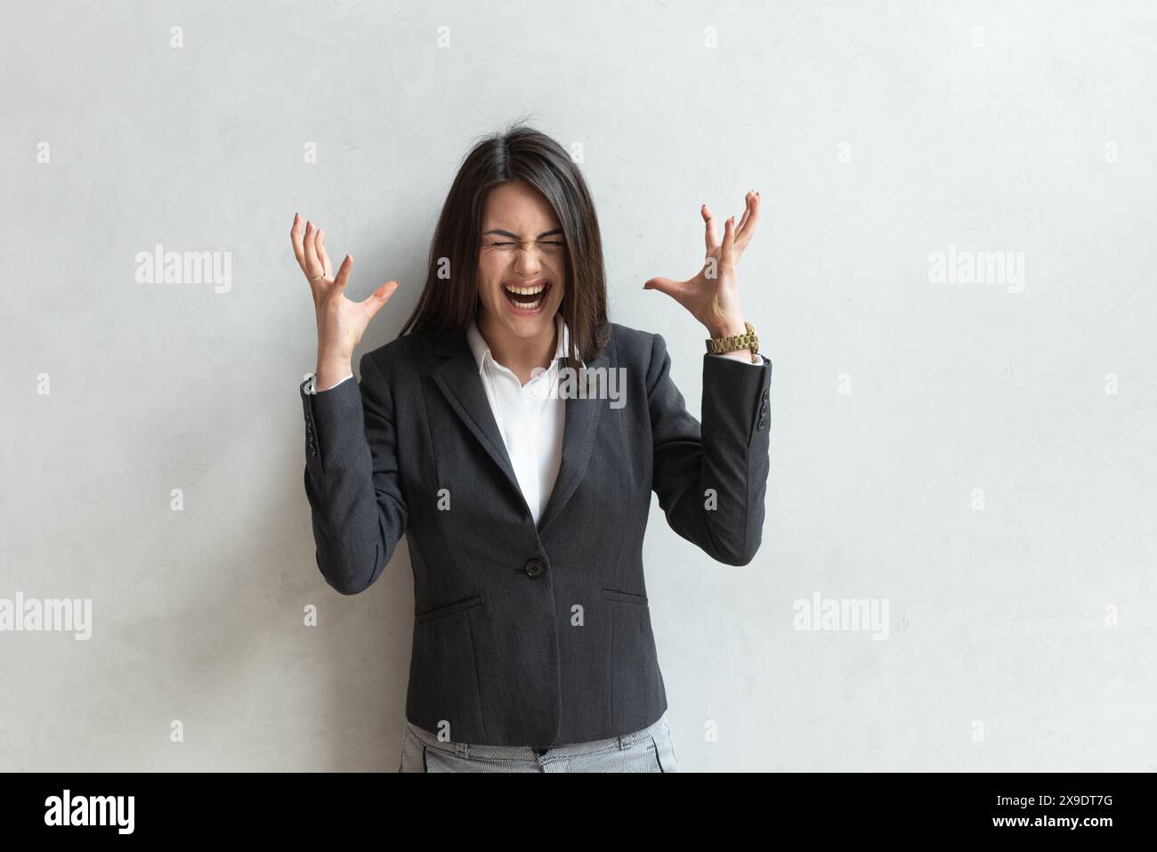 Portrait of young angry frustrated business woman in formal wear standing in office building ...