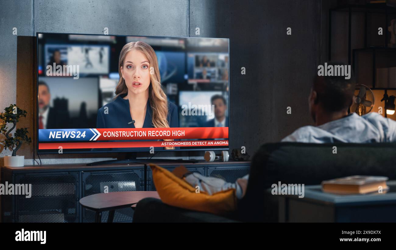 Over the Shoulder View of Black Man Watching TV News, Sitting on Couch ...
