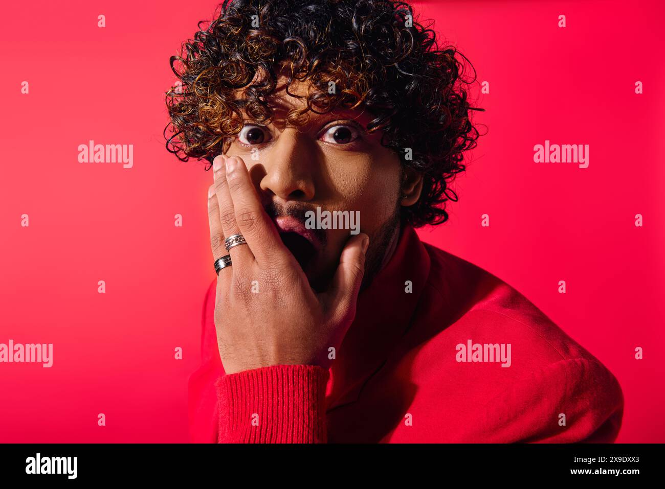 Handsome Indian man with curly hair strikes a pose in a bright red ...