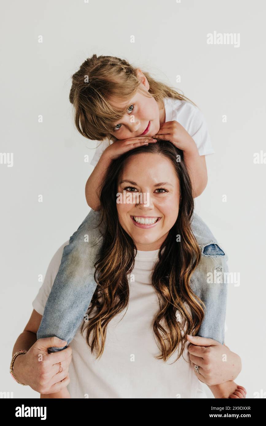 Young girl sits on mom's shoulders while resting her head on hands ...