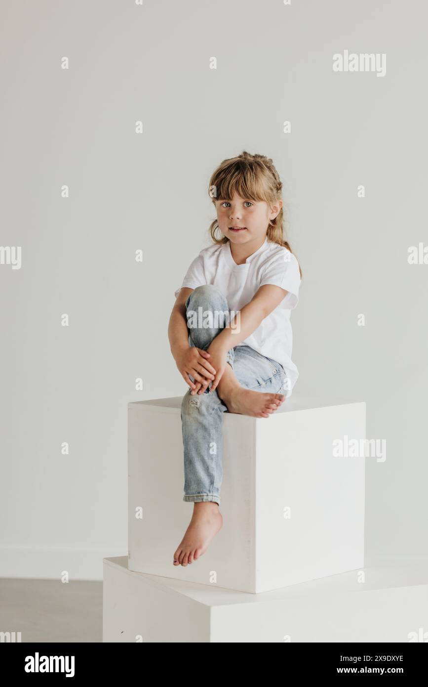 Young girl sits on stack of posing blocks while looking at camera Stock ...