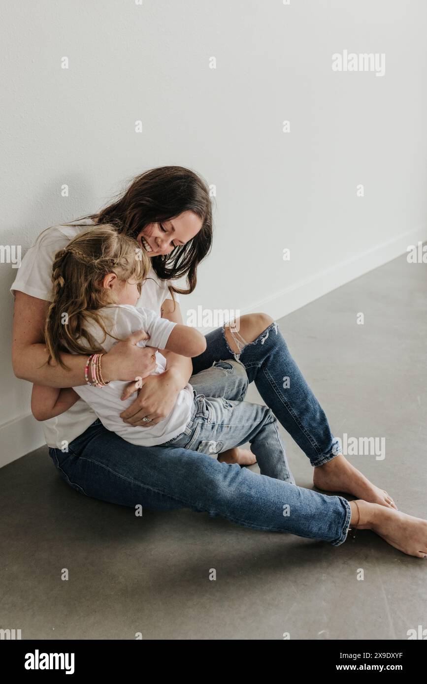 Mother and daughter sit on floor snuggled up together Stock Photo - Alamy