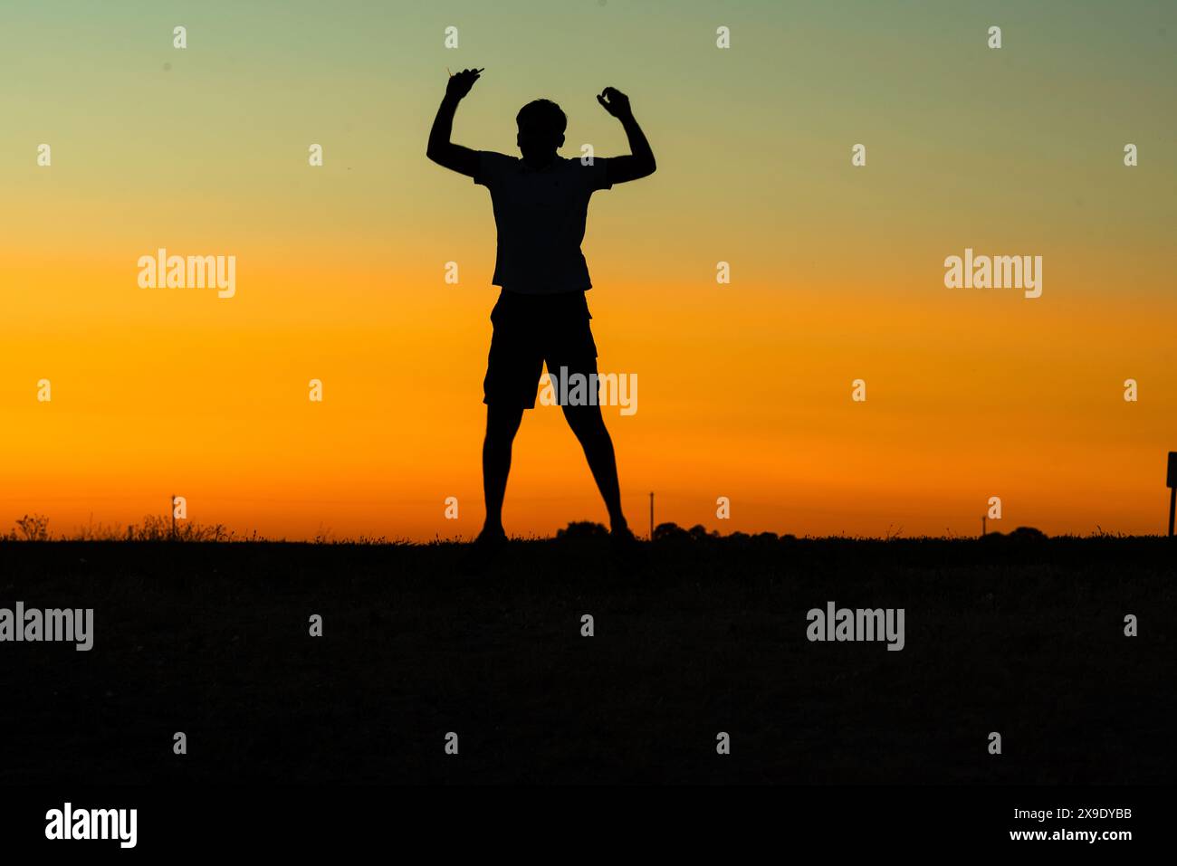Silhouette of a person jumping against a vibrant sunset sky Stock Photo ...